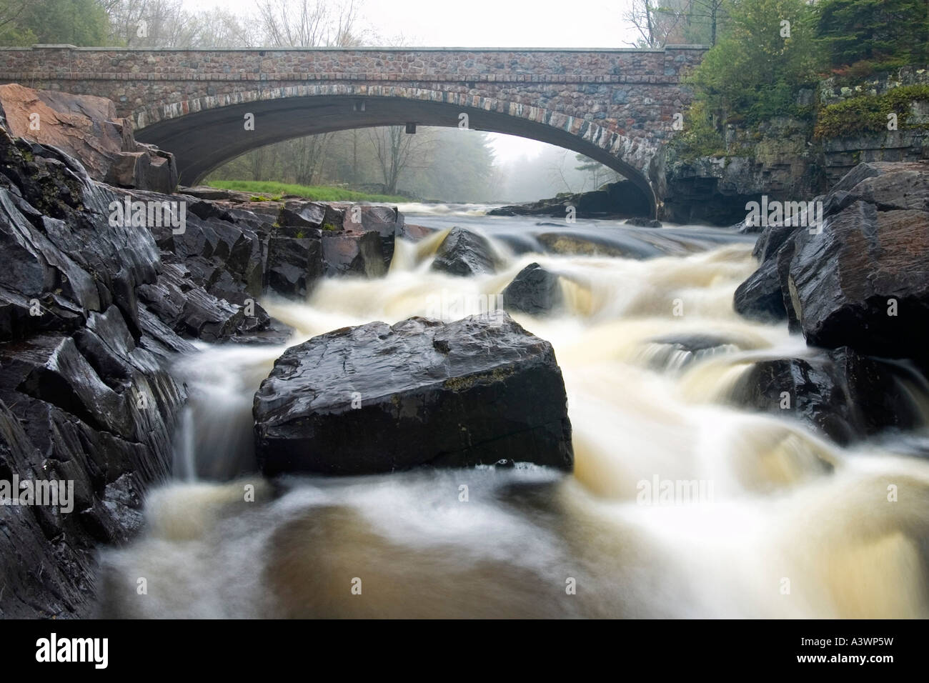 A stone bridge crosses the Eau Claire River at the Dells of the Eau ...