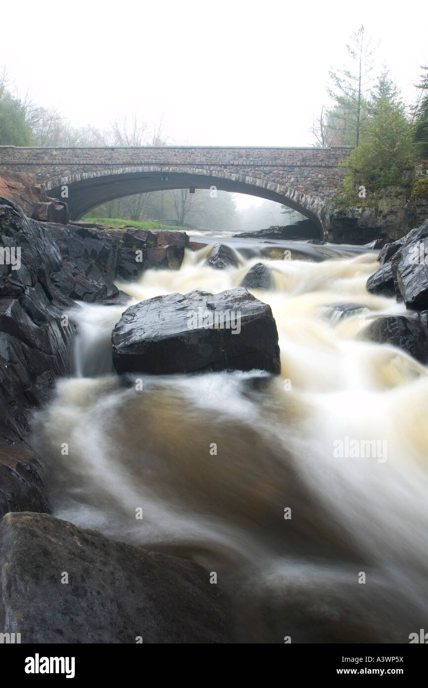 A stone bridge crosses the Eau Claire River at the Dells of the Eau ...