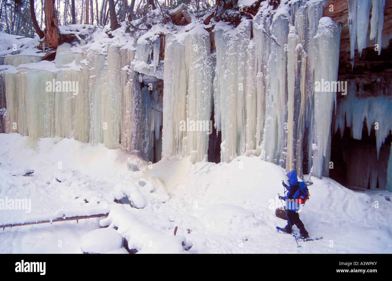 A SNOWSHOER HIKES PAST ICE CAVES IN THE ROCK RIVER CANYON WILDERNESS ...