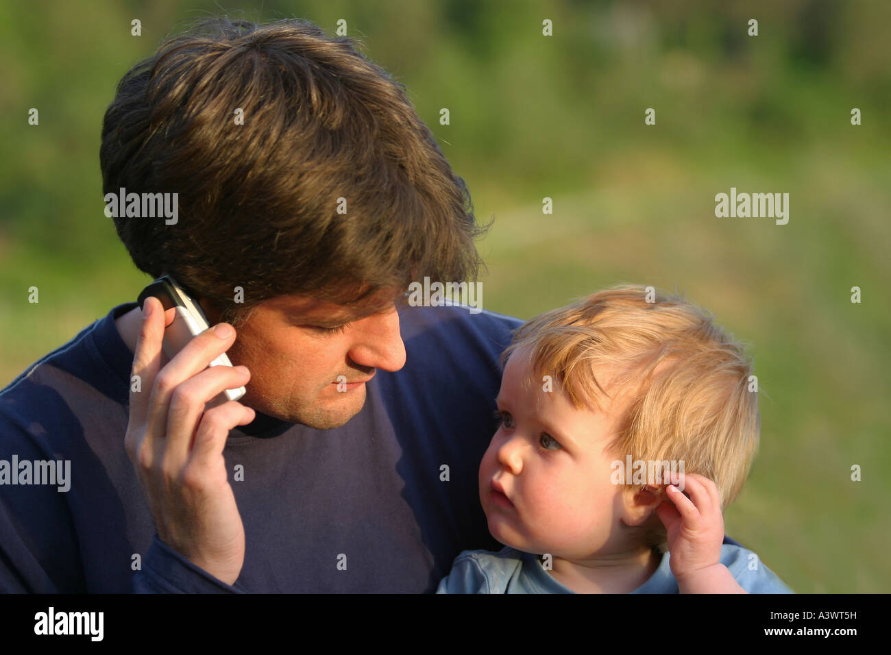 A young son mimics his father who is talking on his mobile Stock Photo ...
