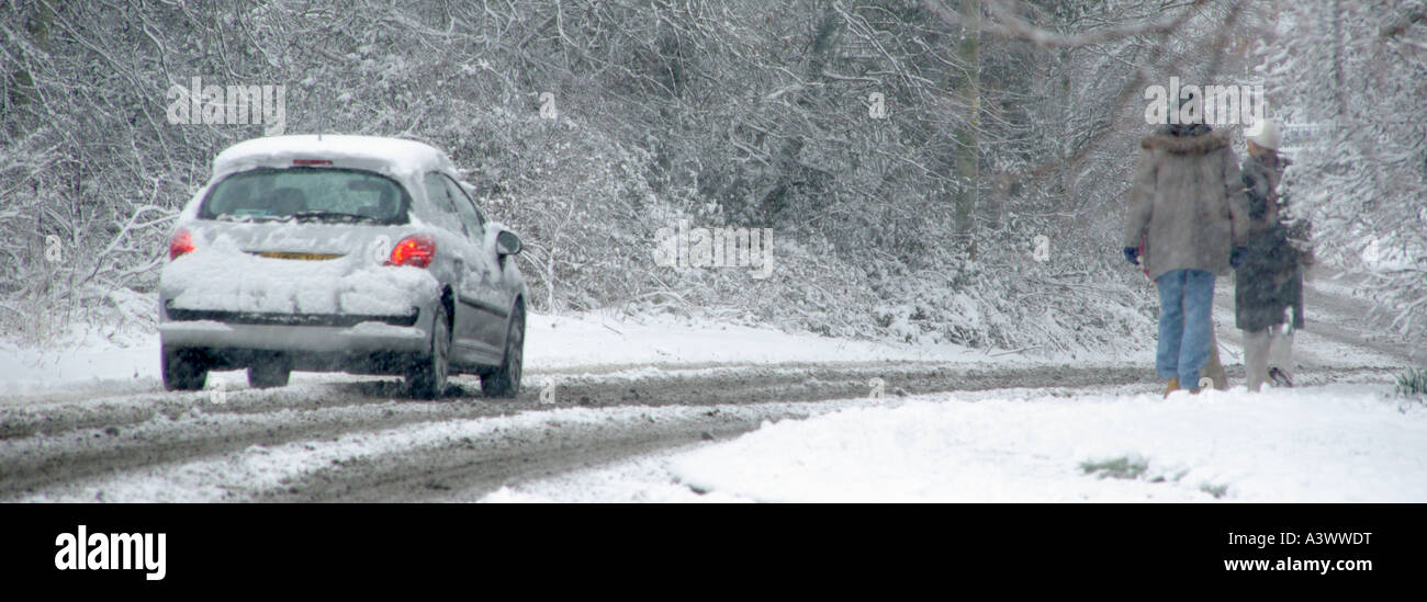 Country road with snow falling car driving along with rear red lights ...