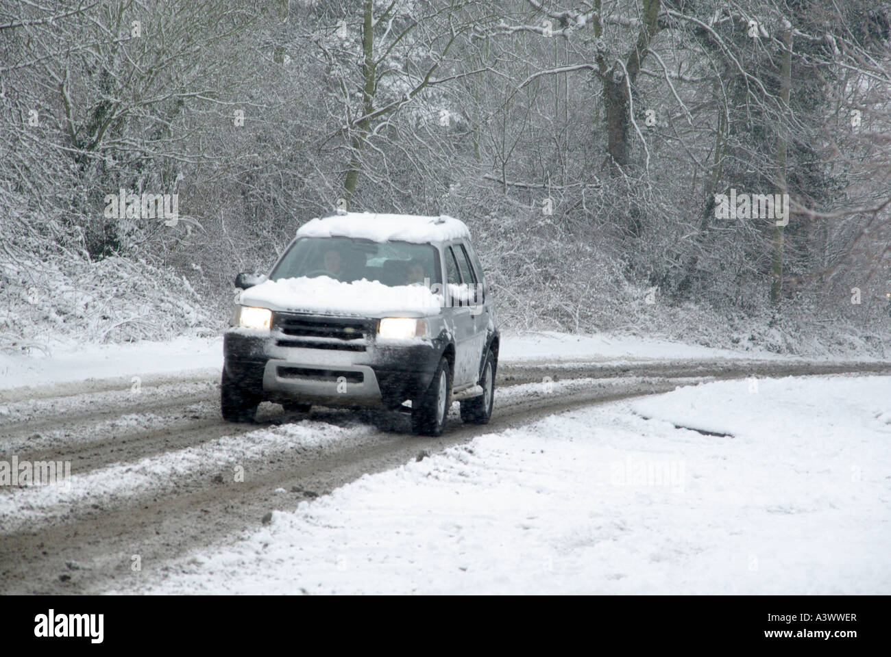 Country road with snow falling car driving along with headlights on ...
