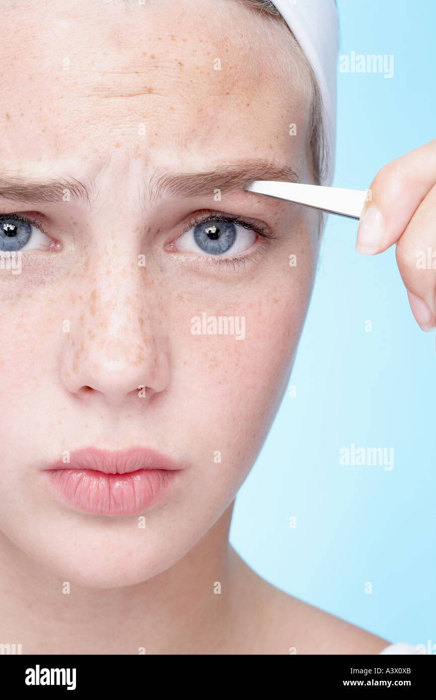 A young woman plucking eyebrows close up Stock Photo - Alamy