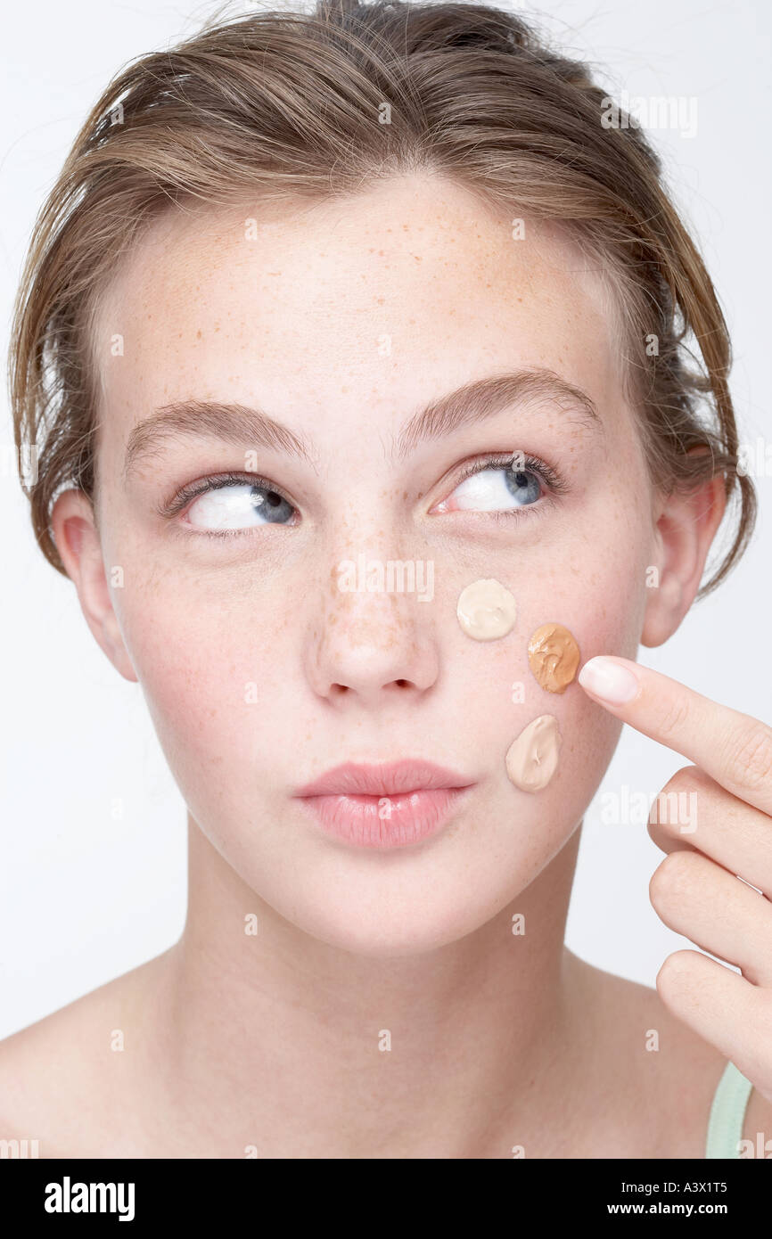 A young woman applying foundation on her face close up Stock Photo - Alamy