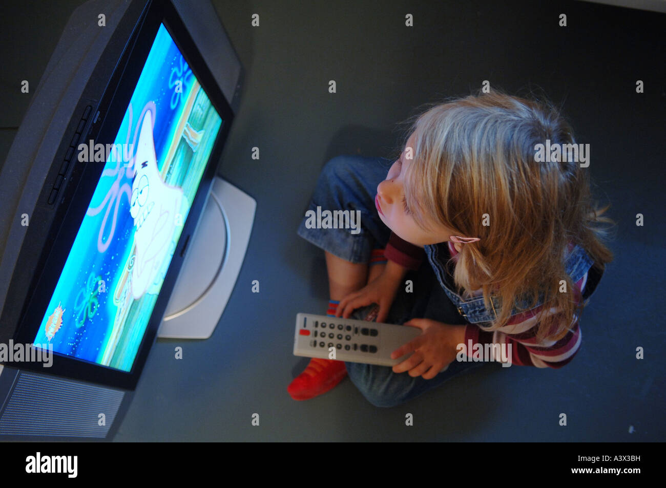 Young girl of four years watching a children channel on television ...