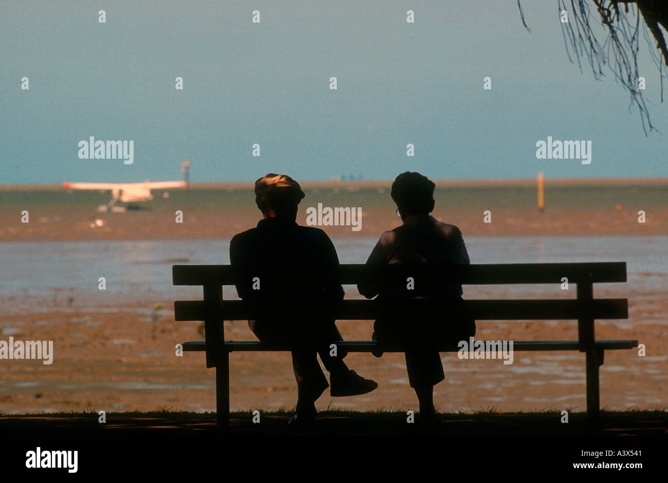 Couple on esplanade bench Cairns Harbour Trinity Inlet at low tide ...