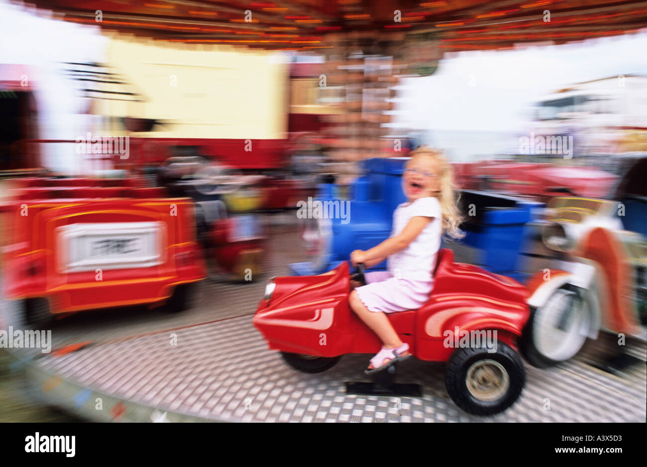 young girl on a fairground roundabout ride smiling and laughing blurred ...