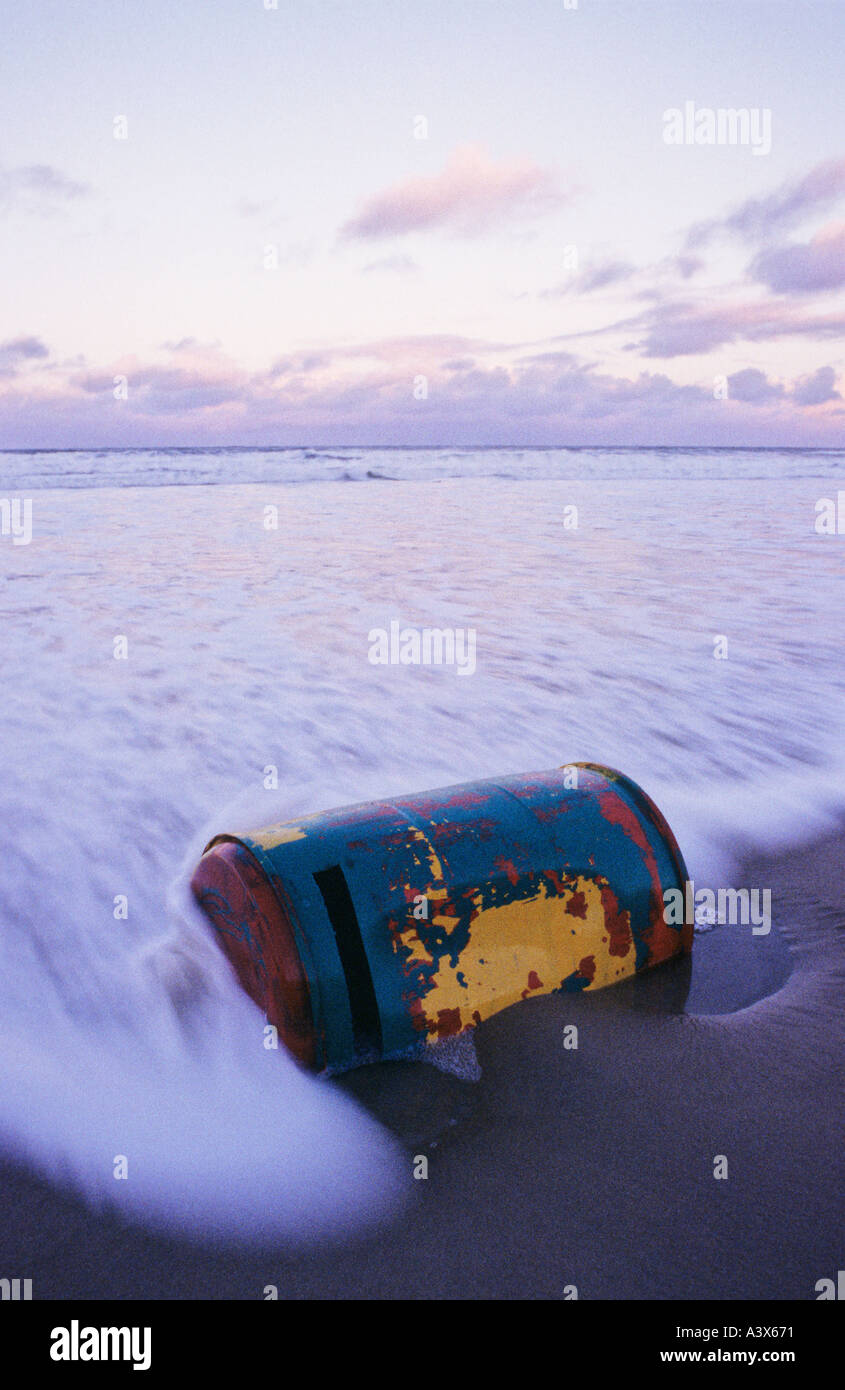 chemical barrel washed up on the shore with the sea swirling around it ...