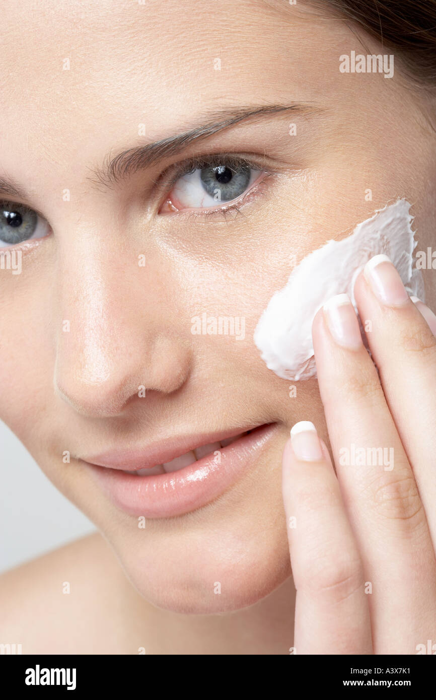 Young woman applying cream on face Stock Photo - Alamy