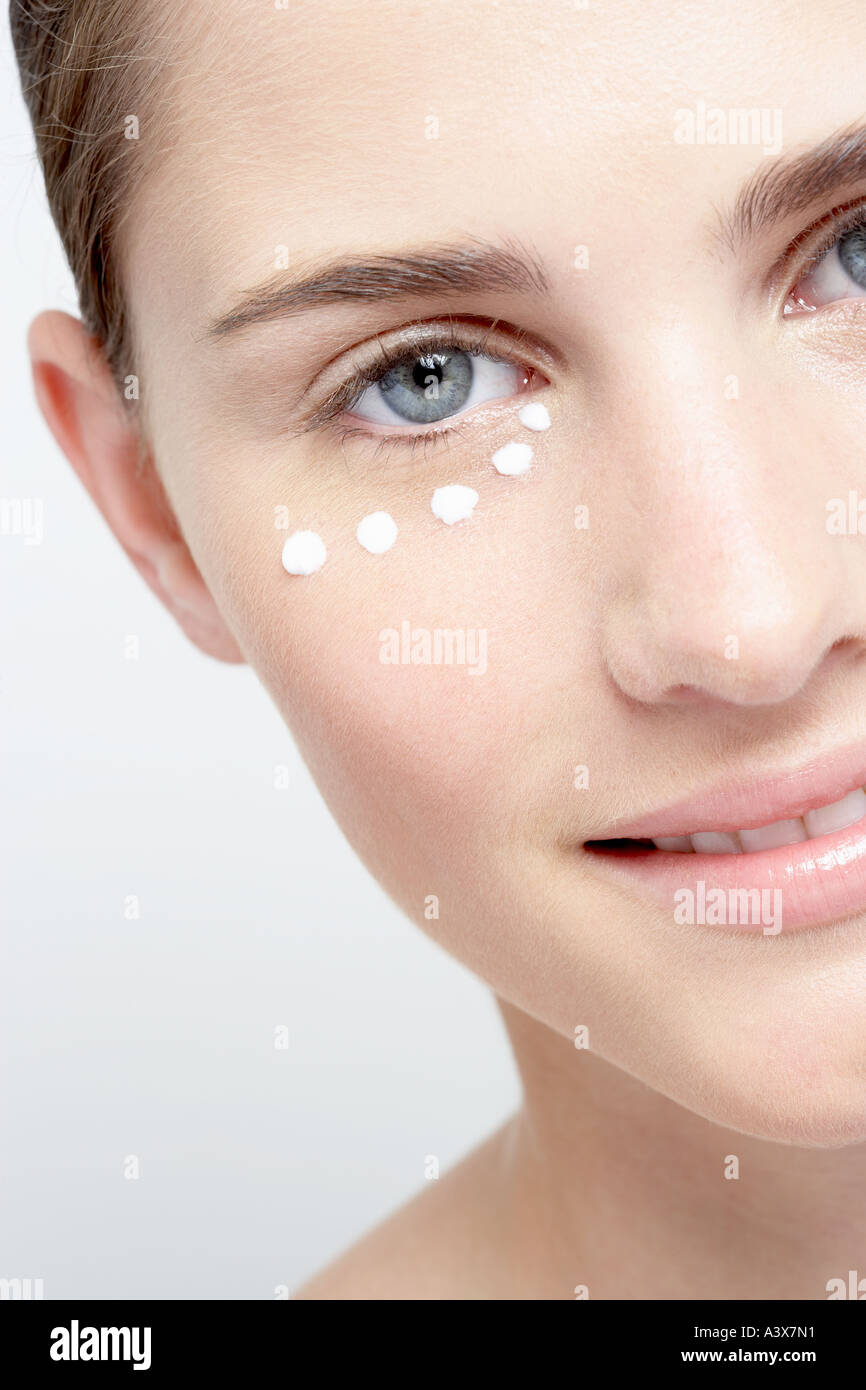 Young woman with cream under her eye Stock Photo - Alamy