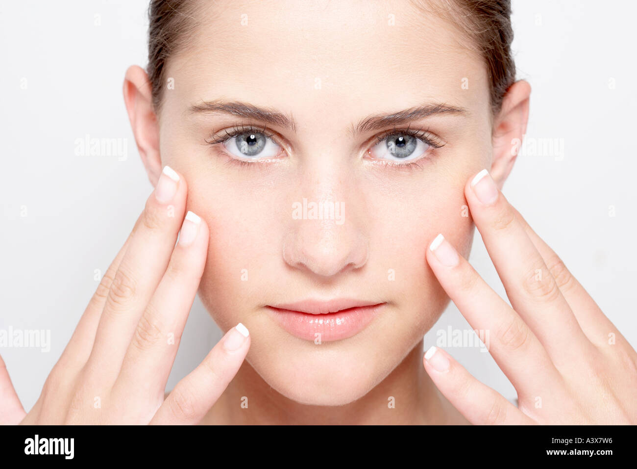 Young woman holding hands to face looking at camera Stock Photo - Alamy