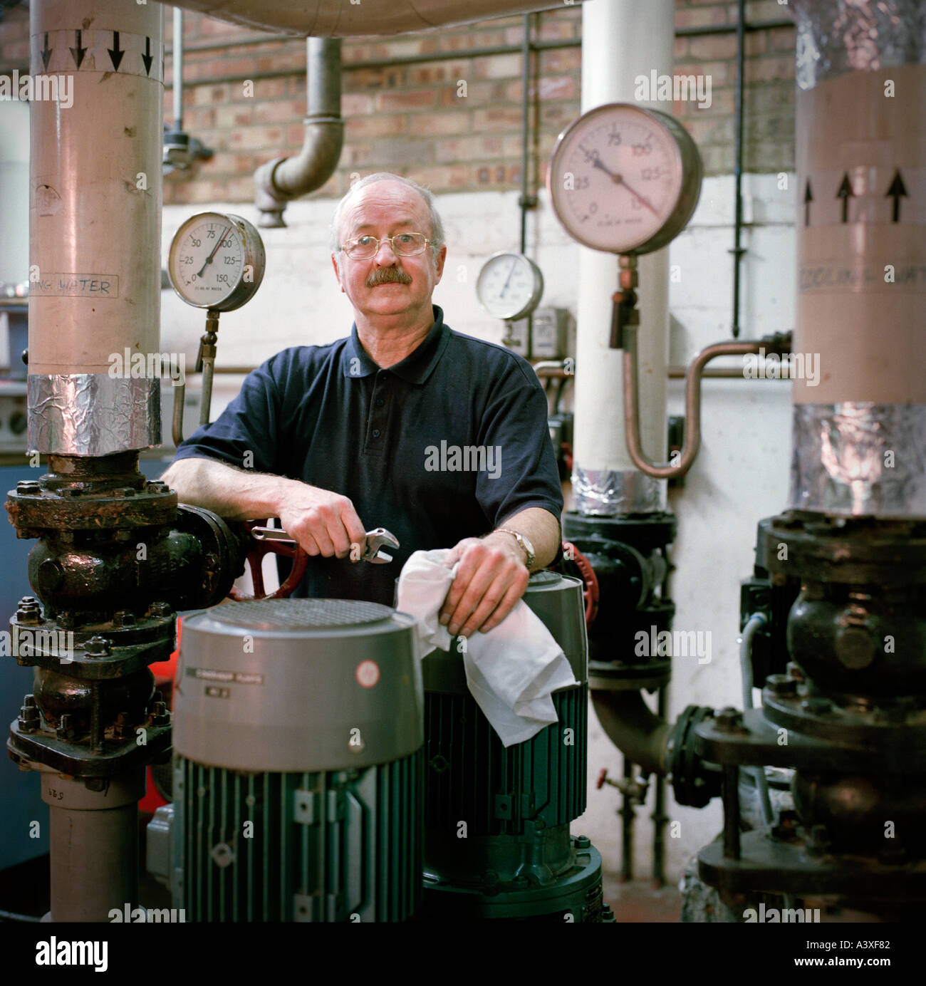 Older man working with a heating system in the basement of a London ...