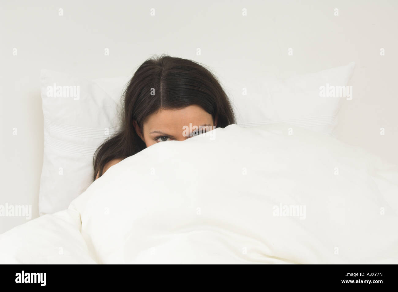 young woman hiding in bed behind duvet Stock Photo - Alamy