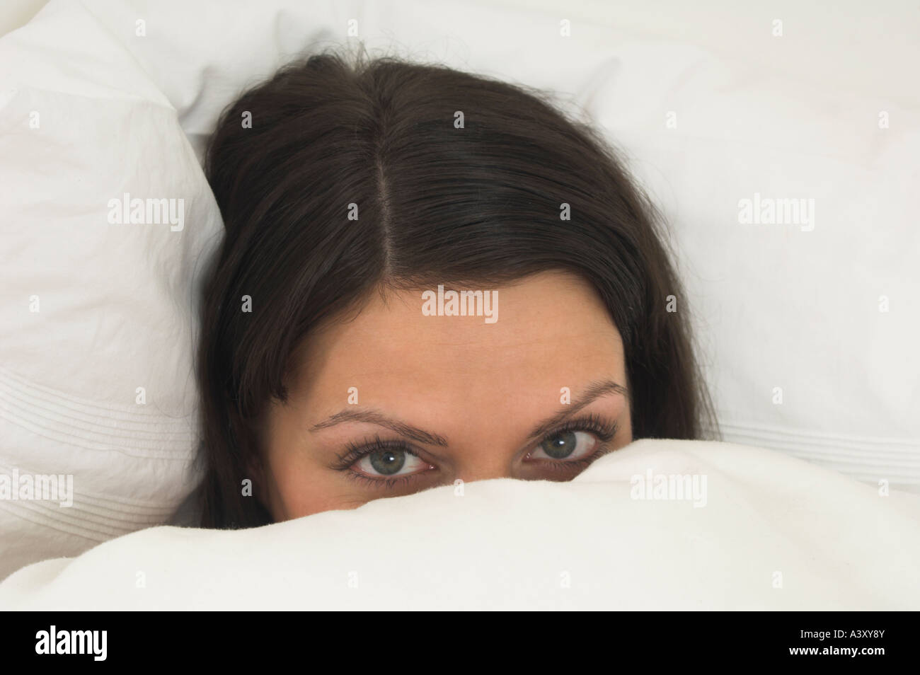 young woman hiding in bed behind duvet Stock Photo - Alamy