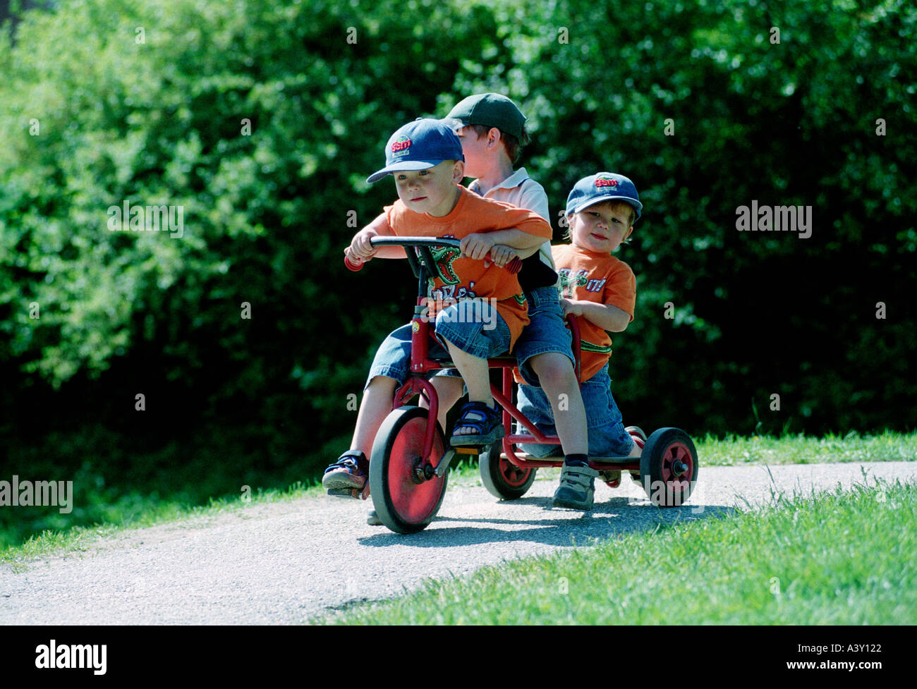 3 boys on a tricycle Stock Photo - Alamy