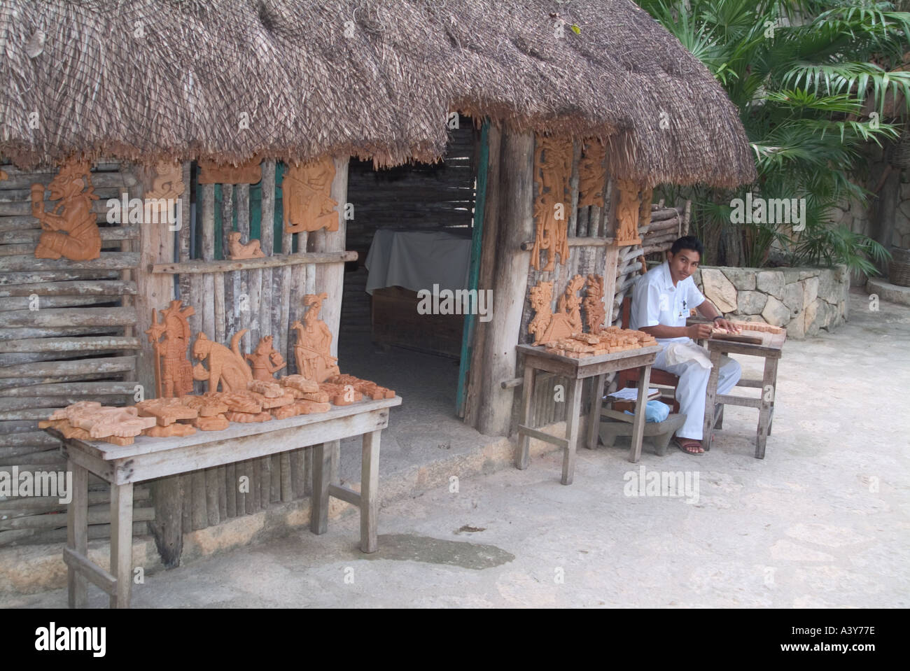 Mayan man in front of wooden hut displaying and working on wooden ...