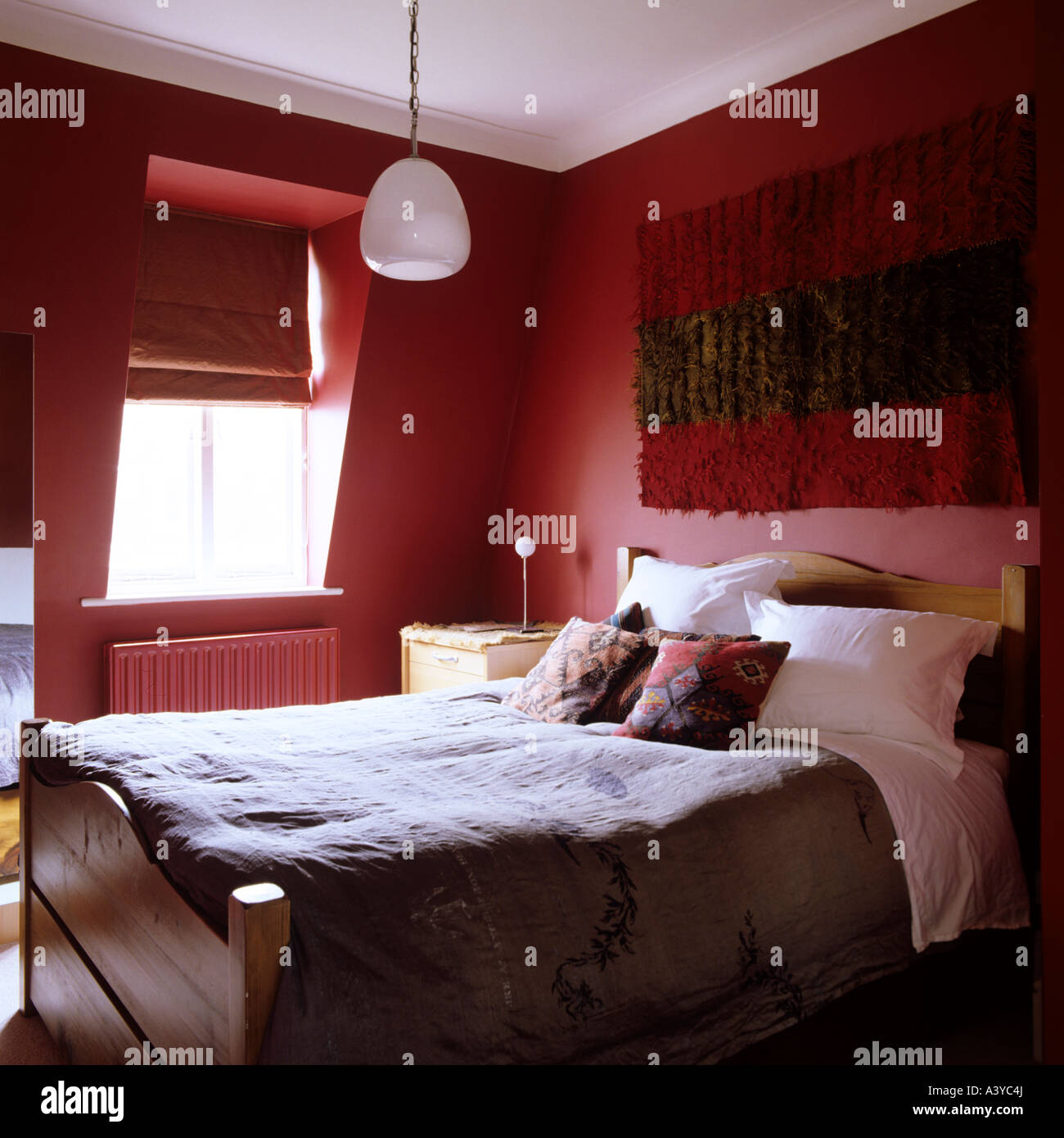 Deep red bedroom with wall hanging Stock Photo - Alamy