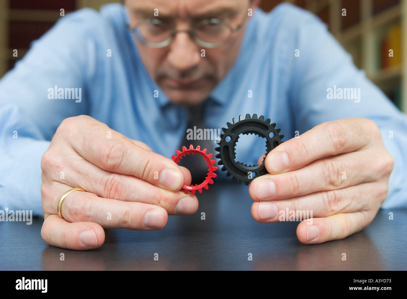 Exact control man looking at two cogwheels Stock Photo - Alamy