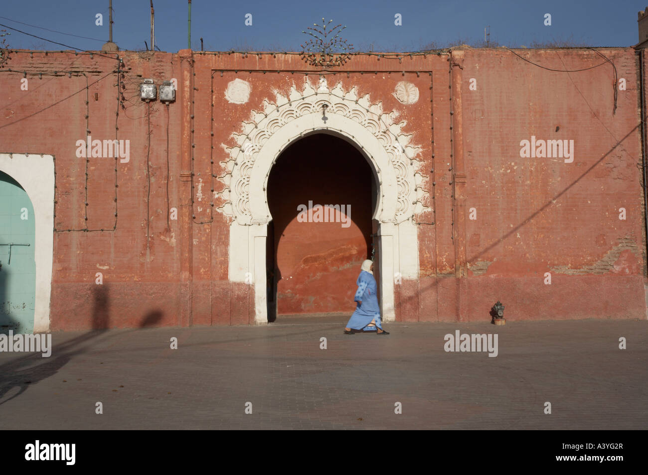 A woman in traditional clothes is walking past an archway in Marrakech ...