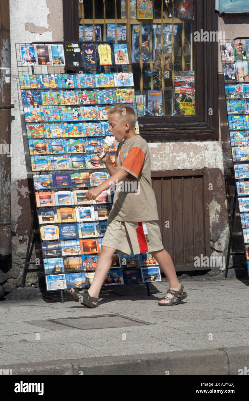 A boy eating an ice cream is walking past a shop Stock Photo - Alamy