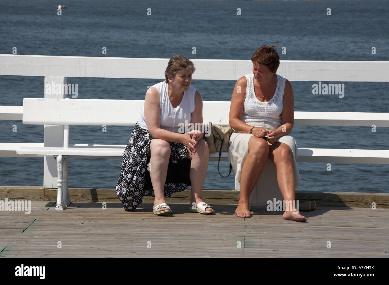 Two mature women talking on a bench Stock Photo - Alamy