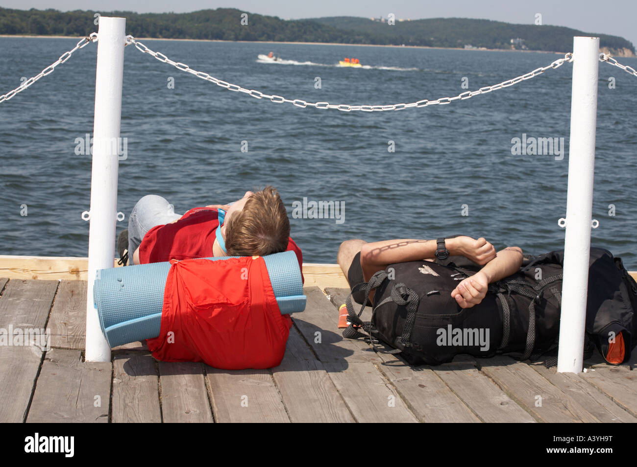 Two young travellers sleeping beside the sea on a jetty Stock Photo - Alamy