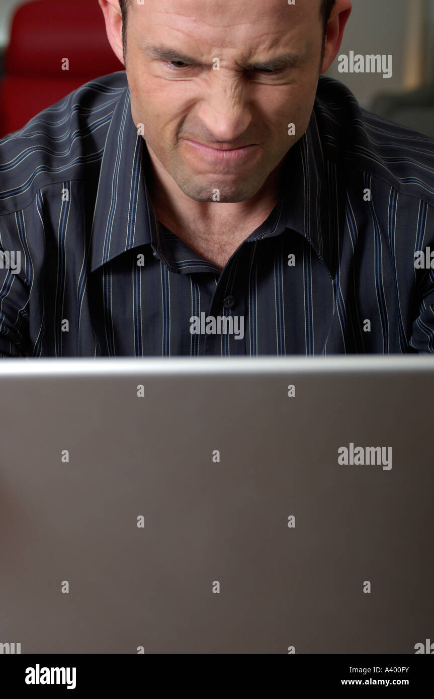 portrait of angry man looking frustrated at screen of laptop computer ...