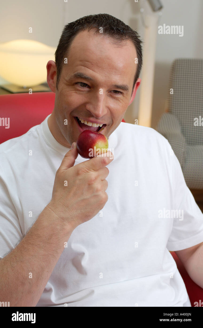young man biting into red apple Stock Photo - Alamy