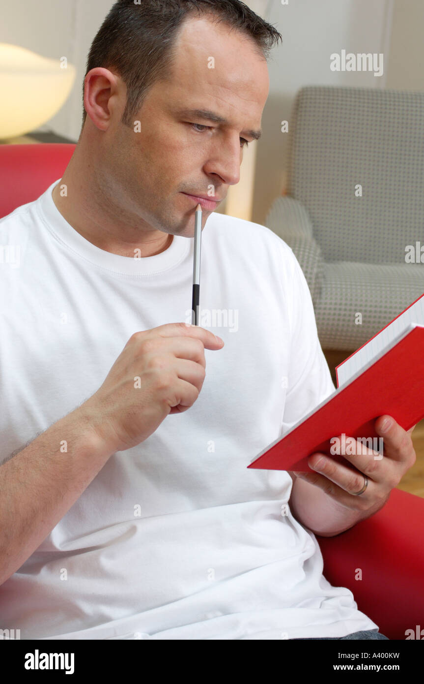 portrait of young man holding journal and pen thinking Stock Photo - Alamy