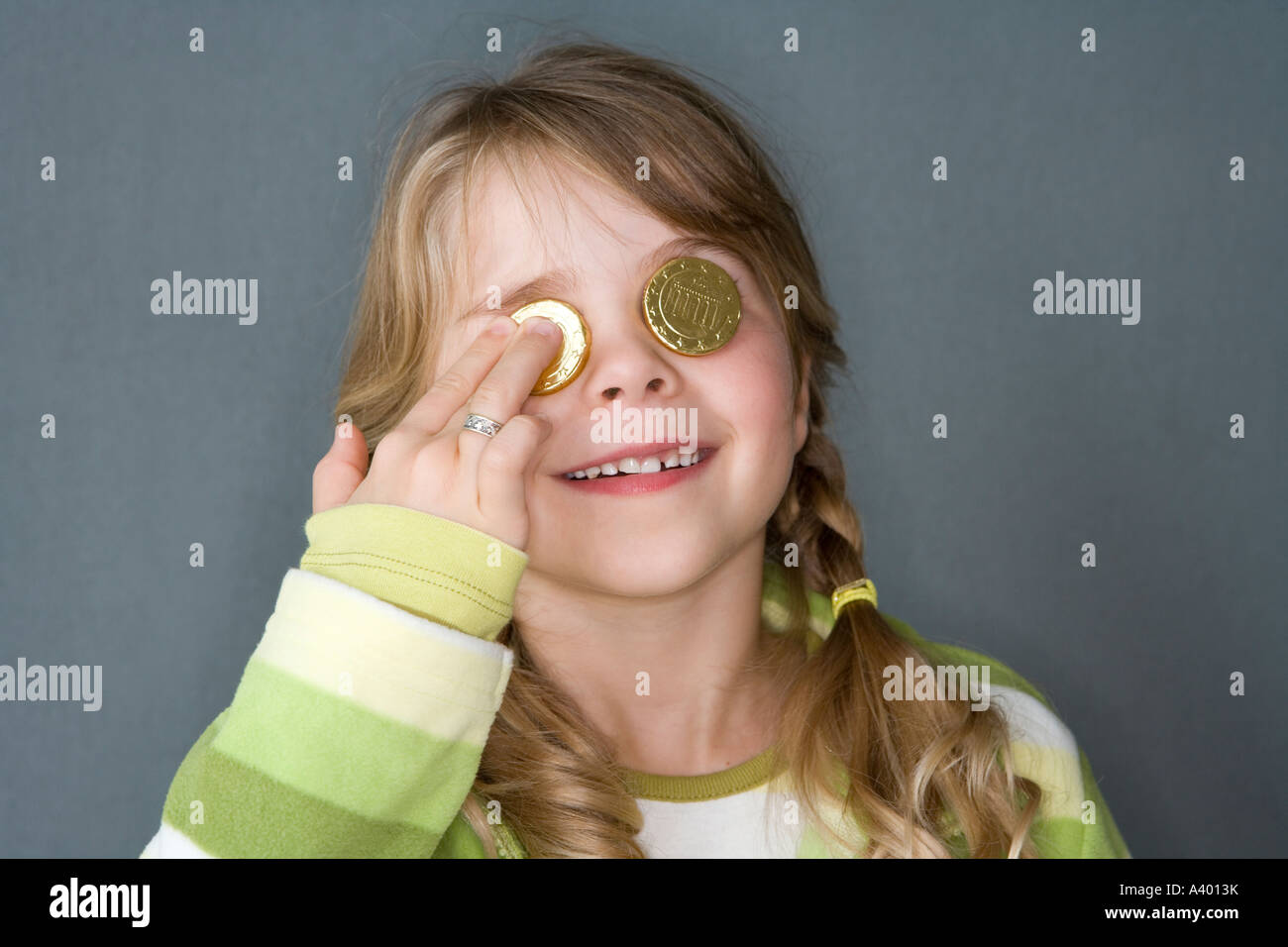 little girl in green covering her eyes with Euro coins Stock Photo - Alamy