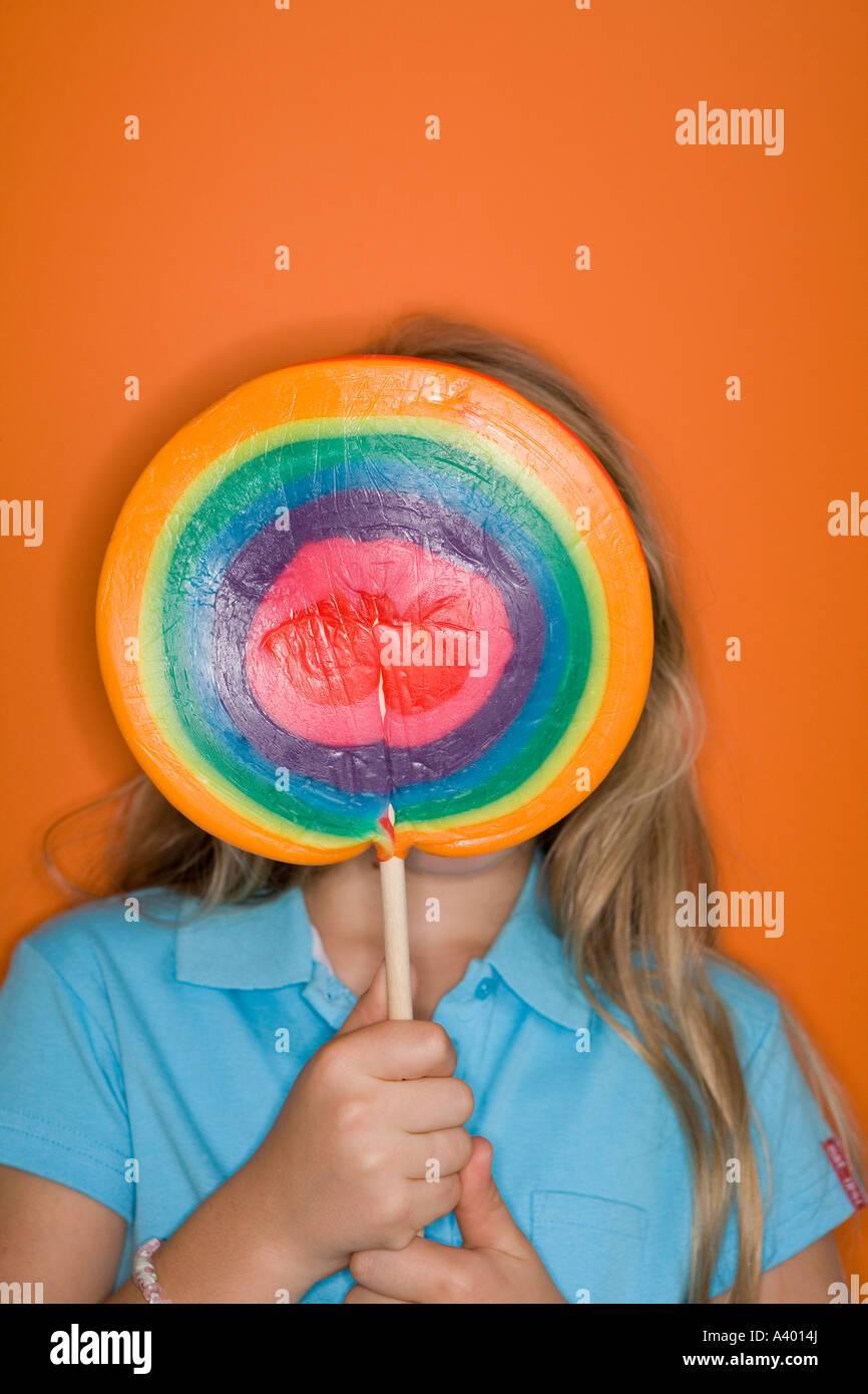 young girl hiding behind large colorful lollipop Stock Photo - Alamy