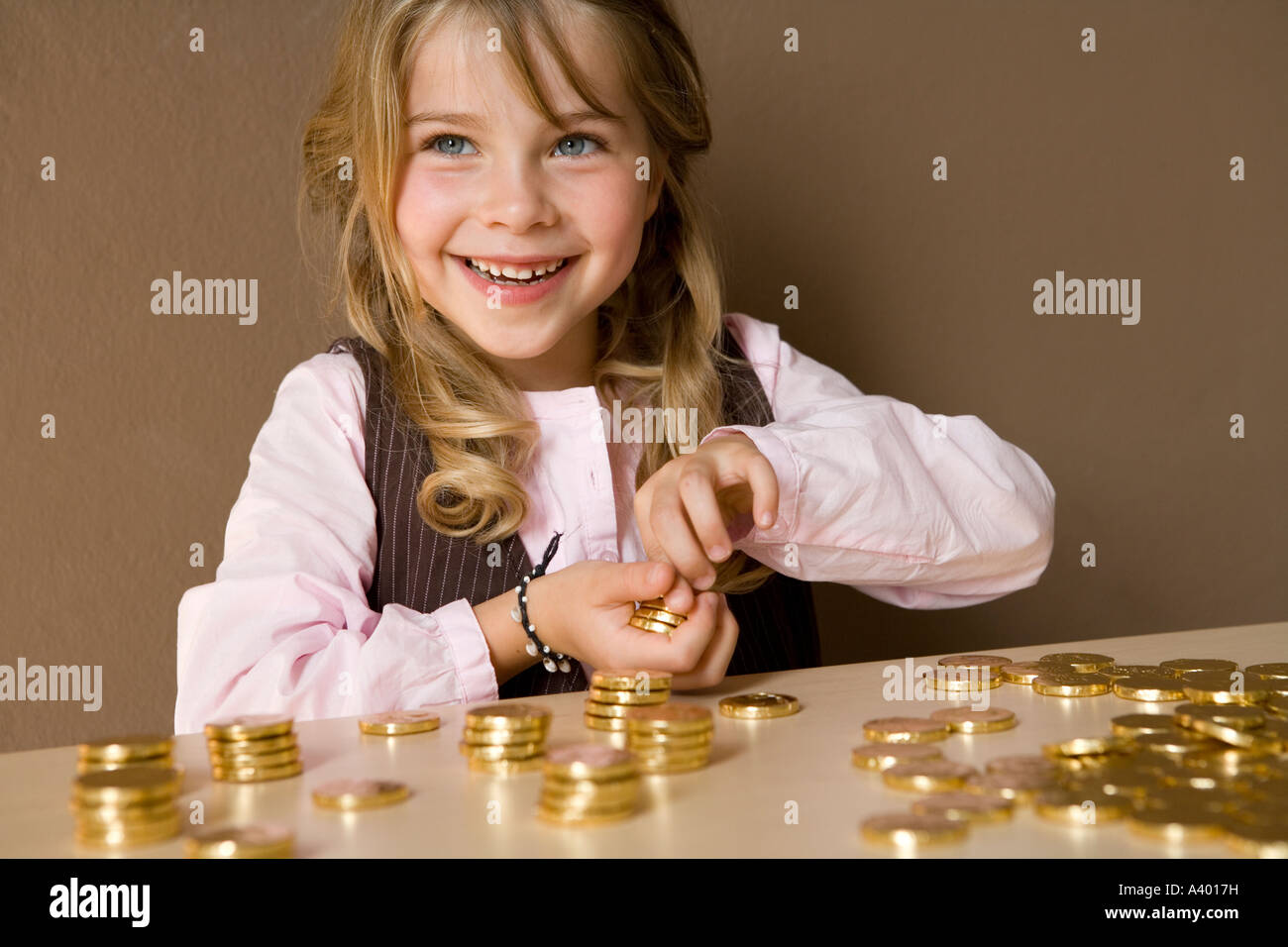 smiling young girl playing with gold coins Stock Photo - Alamy