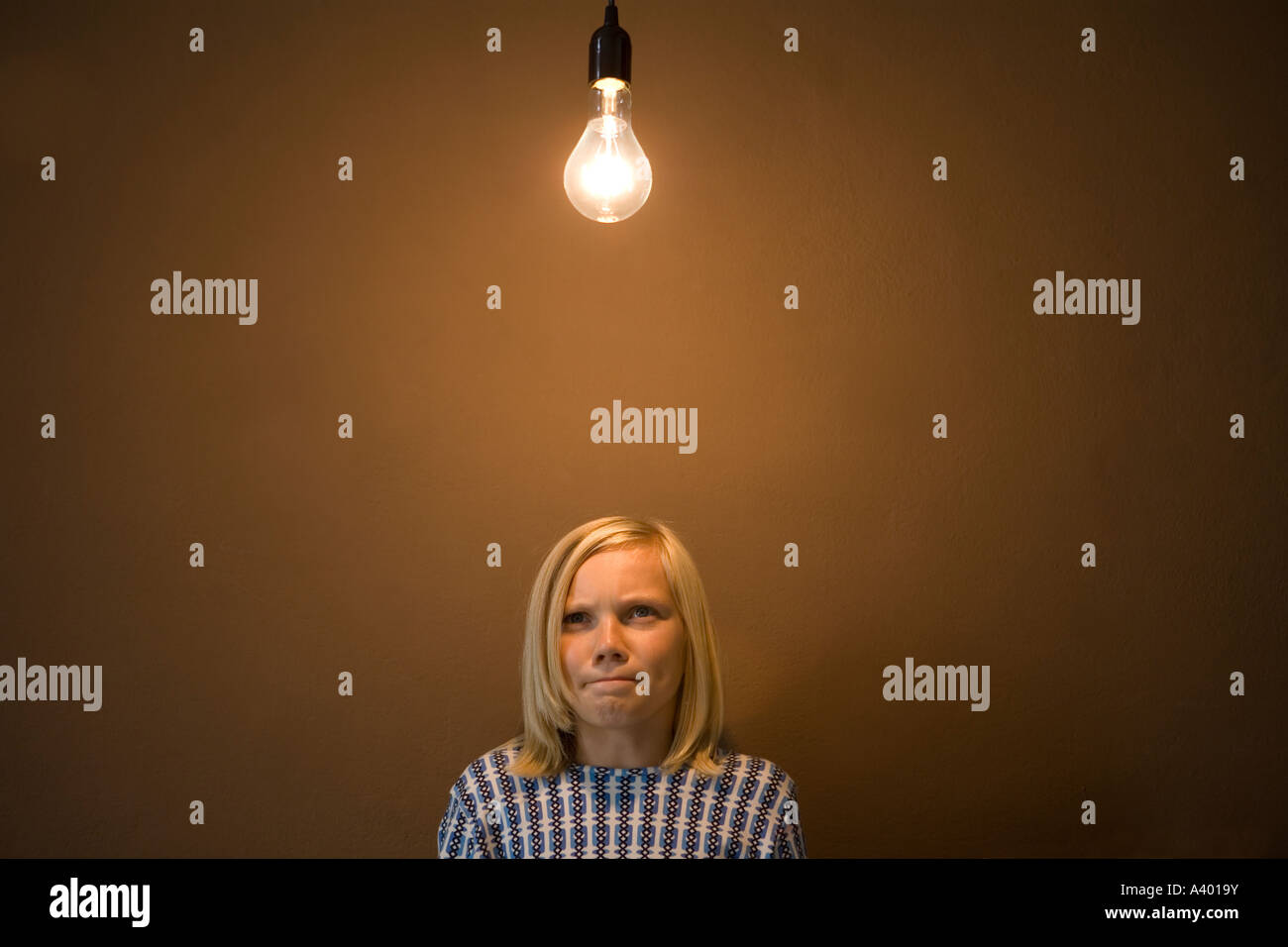 portrait of teenager under lightbulb thinking heavily Stock Photo - Alamy