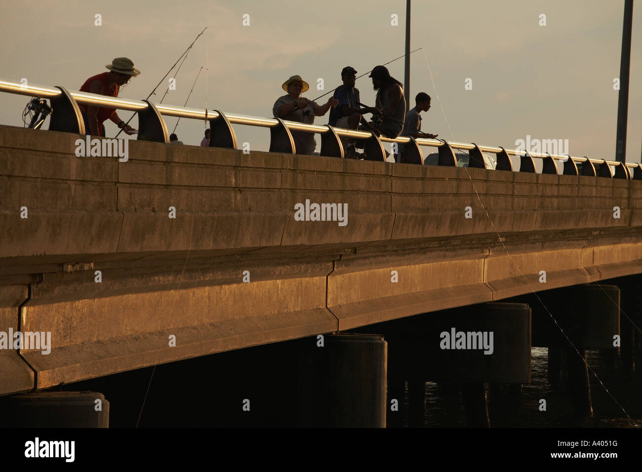 Fisherman fishing from a bridge at sunset Stock Photo - Alamy