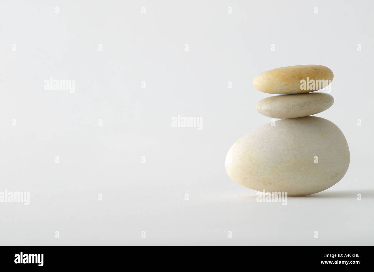Three pebbles balanced with a white background Stock Photo - Alamy