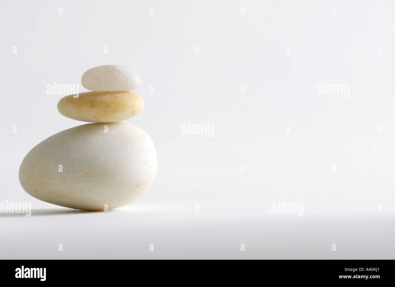 Three pebbles balanced with a white background Stock Photo - Alamy
