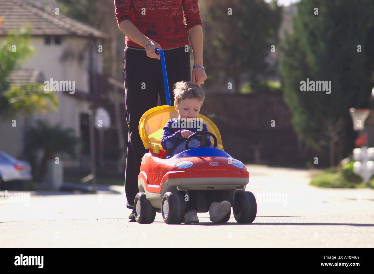 mother pushing boy on toy Stock Photo - Alamy