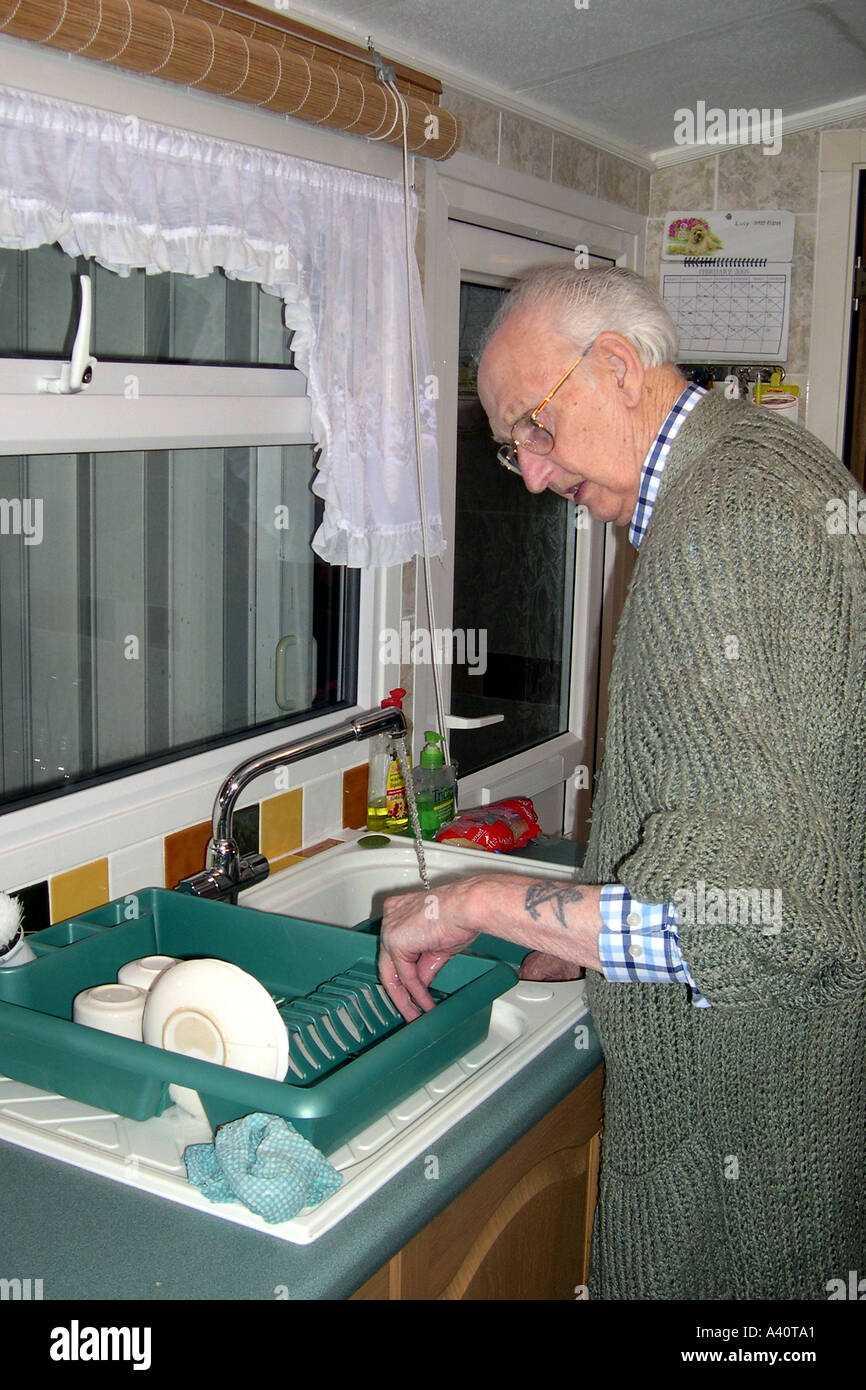 Senior male doing domestic chores in the kitchen washing up dirty ...