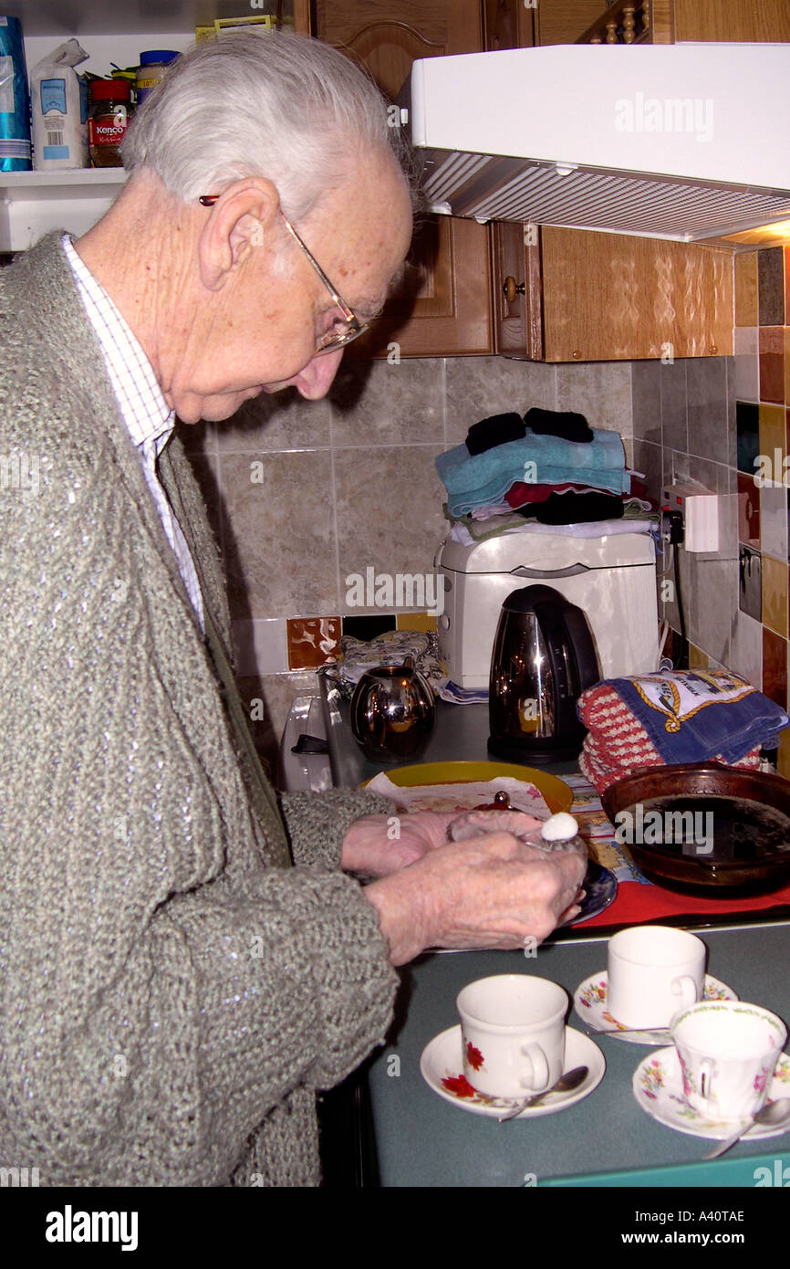 Senior Male making a cup of tea by adding sugar into the cup before the ...