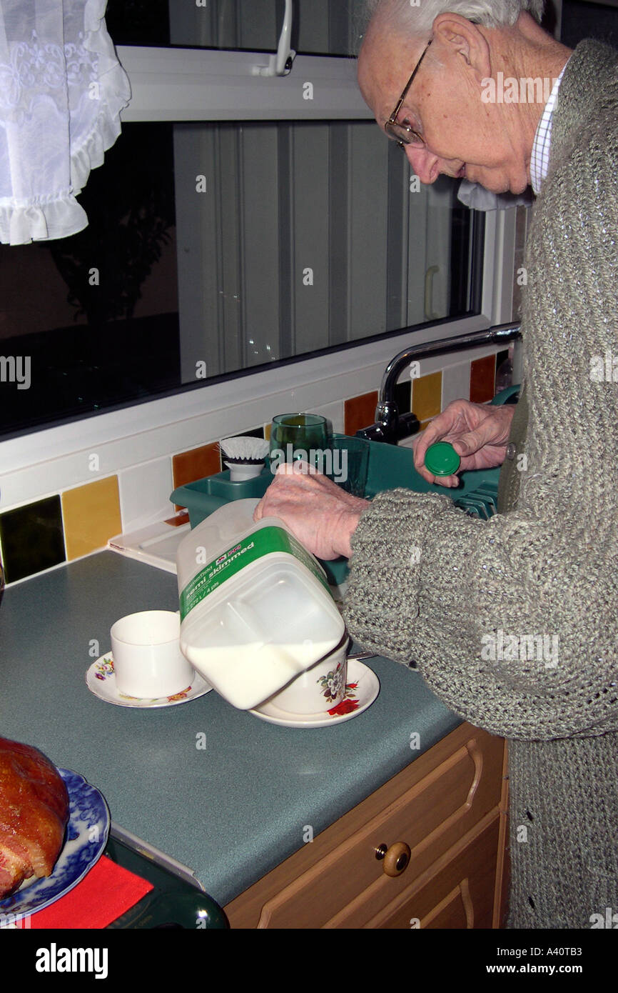 Senior Male making a cup of tea by adding milk into the cup before the ...