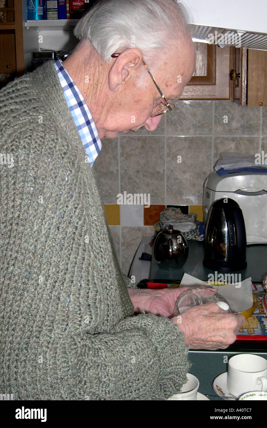 Senior Male making a cup of tea by adding sugar into the cup before the ...