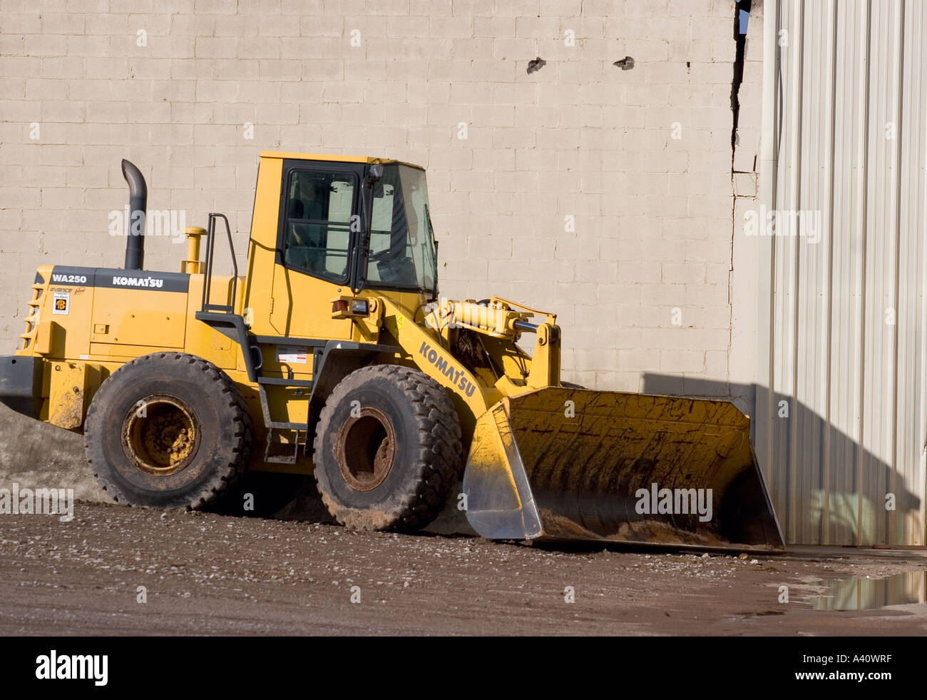 Front end loader against tan metal building Stock Photo - Alamy