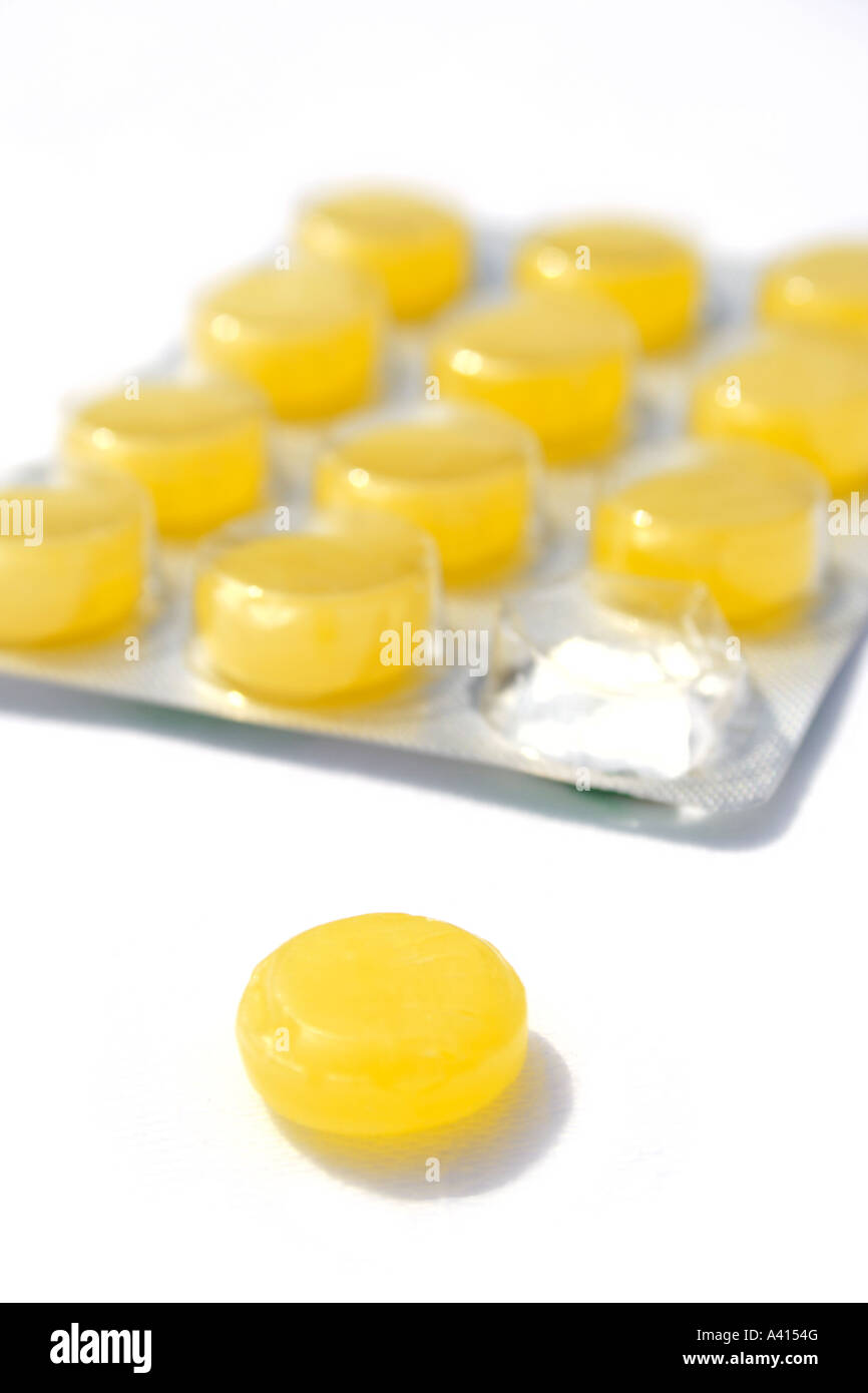 A packet of yellow lozenges with one removed from the packet and placed ...