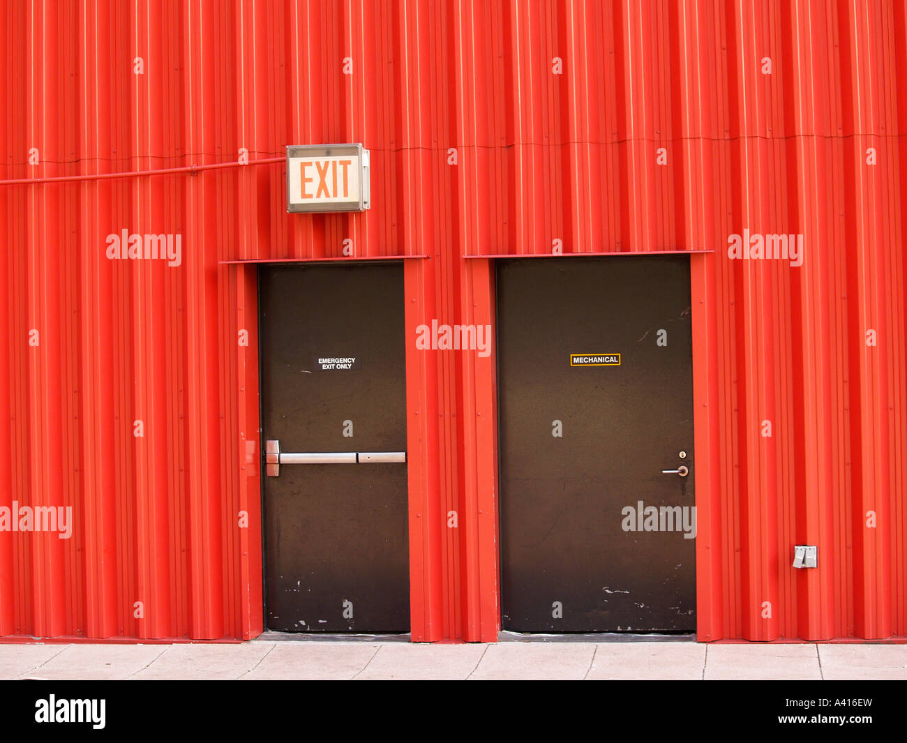 Two brown metal doors in a corrugated metal building with exit sign ...