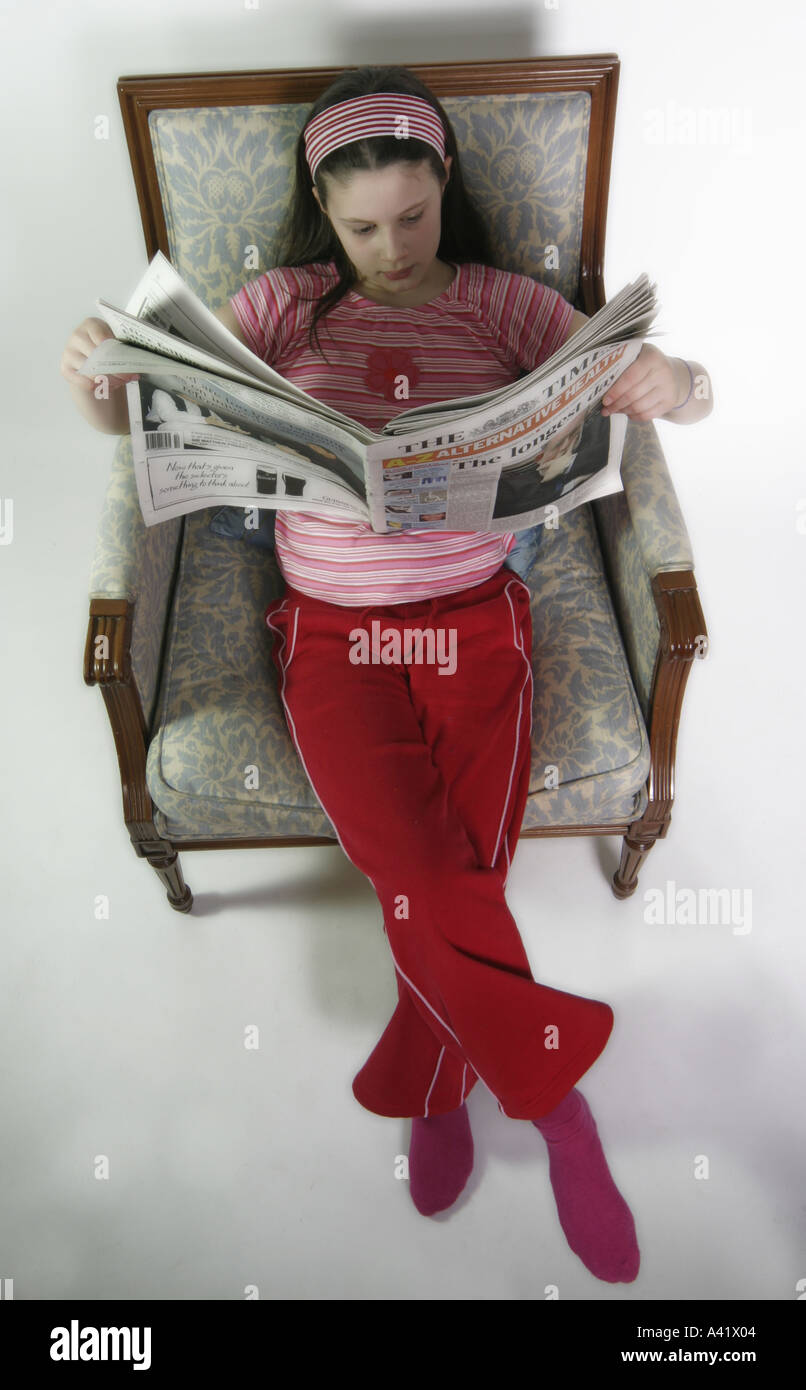 Young girl dressed in red sat on a traditional armchair reading a ...