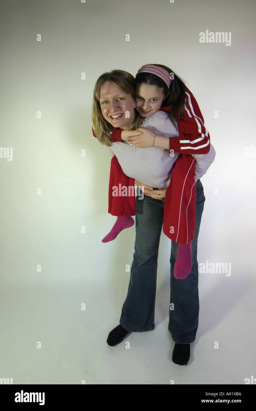 Young woman gives young girl a piggy back Stock Photo - Alamy
