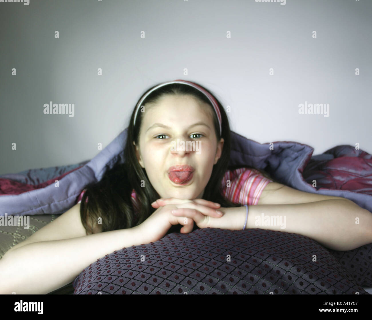 Young girl lay on her front facing the camera pulling a face Stock ...