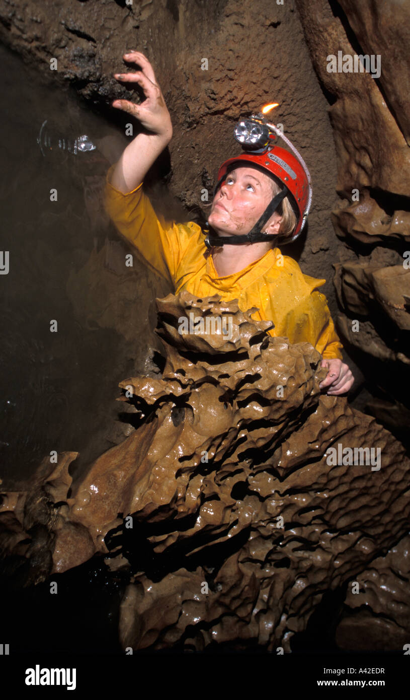 Female caver crawling in narrow stream passage of Clearwater Cave ...