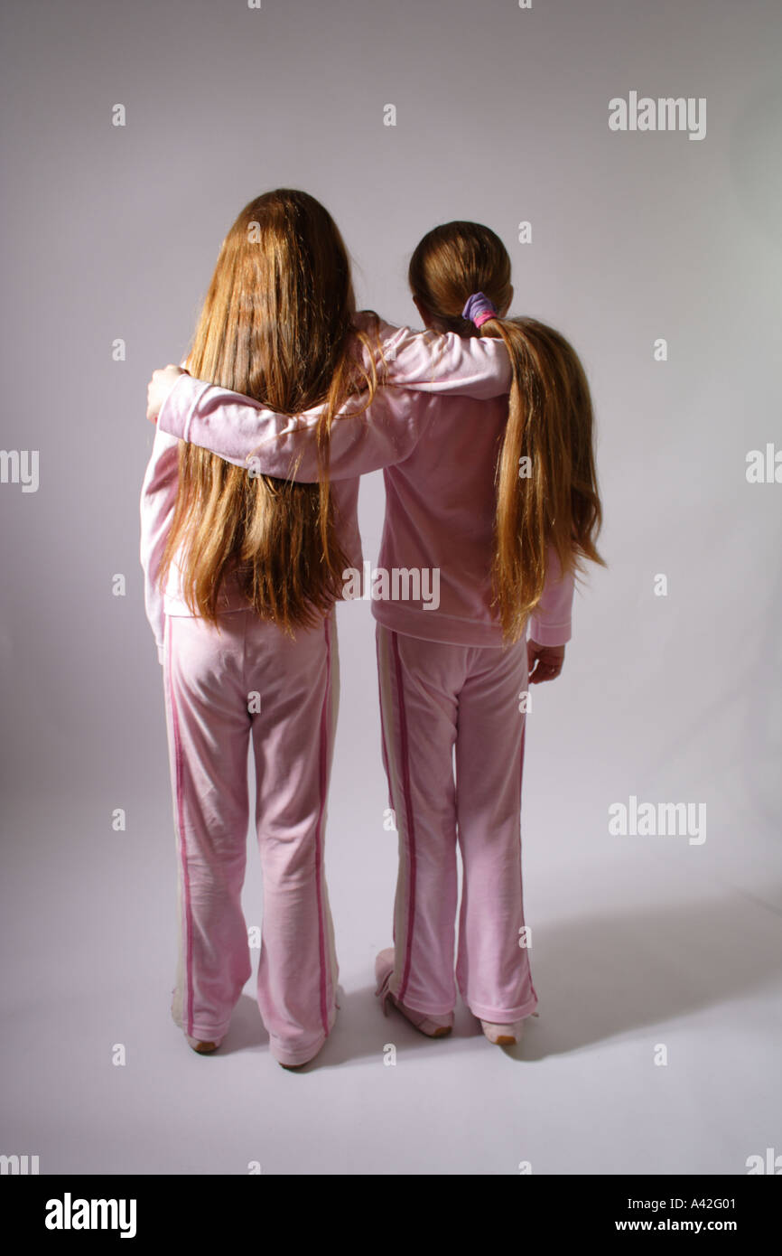 Young twins aged 10 standing upright with their backs to the camera ...