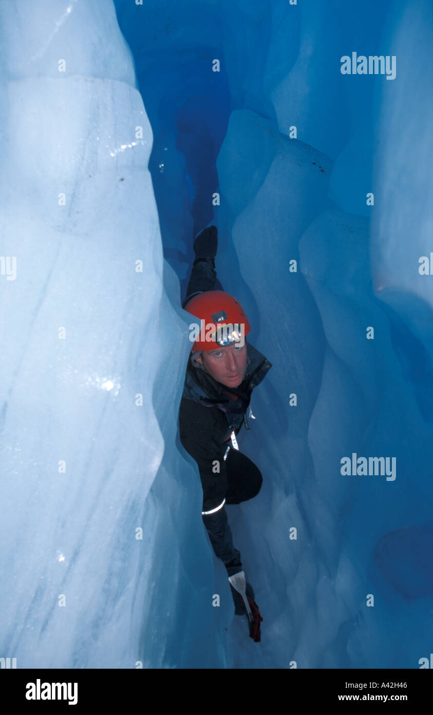 Caver squeezing through a narrow ice cave passage Fox Glacier New ...